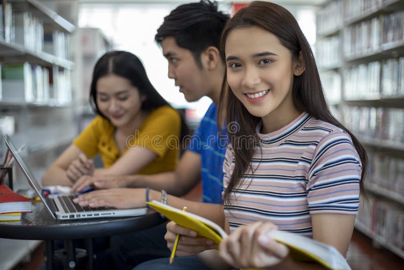 Group Asian Students Smile and Reading a Book and Using the Laptop for ...