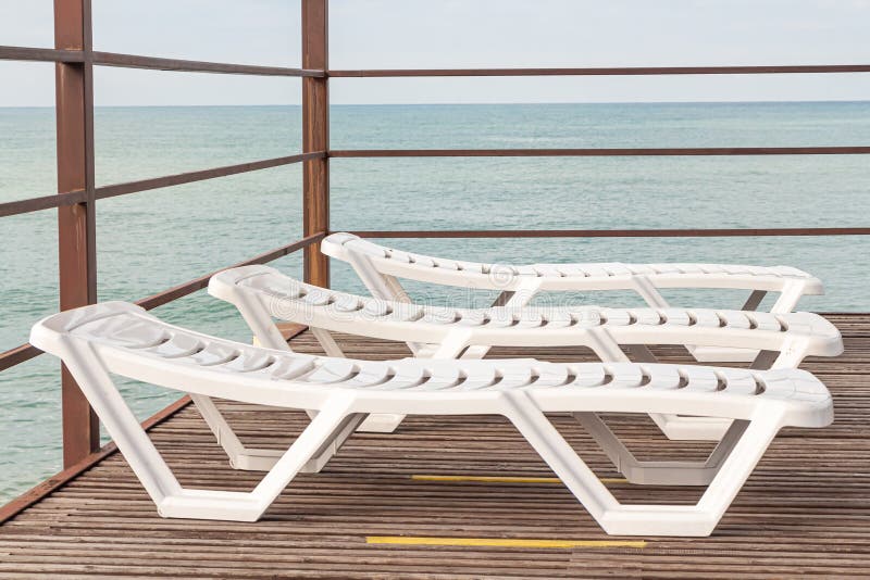 Group of Beautiful White Plastic Sunbeds is on the Beach by Sea Stock ...