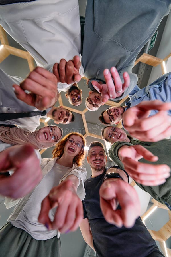 A Group of Cheerful Young People Gathered in a Circle, Pointing at the ...