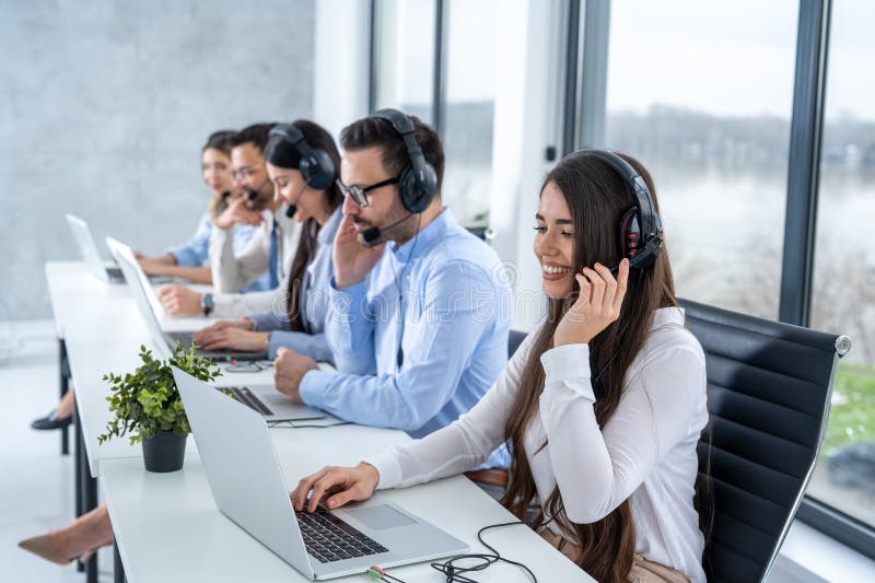 Group of Call Center Workers with Headsets Using Laptops in Office ...