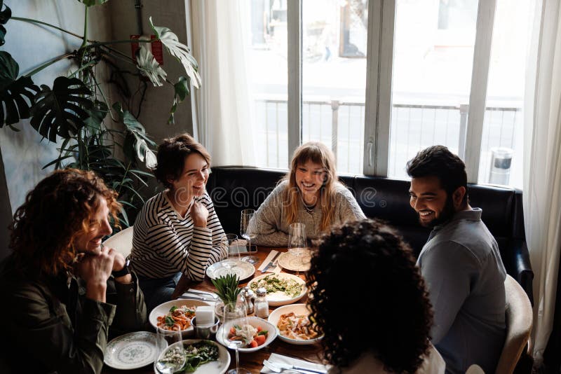 Group of Cheerful Friends Talking while Dining in Restaurant Stock ...
