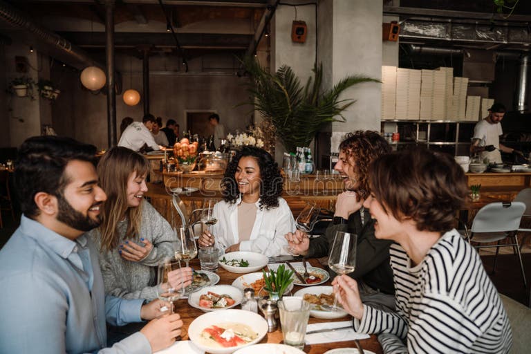 Group of Cheerful Friends Talking while Dining in Restaurant Stock ...