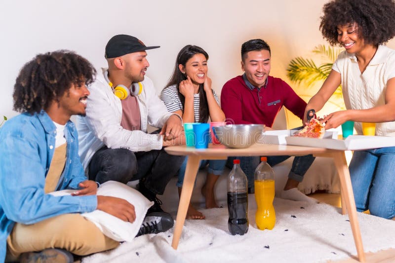 Group of Cheerful Multiethnic Friends on a Sofa Eating Pizza at a Home ... Group of Cheerful Multiethnic Friends on a Sofa Eating Pizza at a Home ...