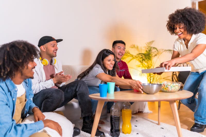 Group of Cheerful Multiethnic Friends on a Sofa Eating Pizza at a Home ... Group of Cheerful Multiethnic Friends on a Sofa Eating Pizza at a Home ...