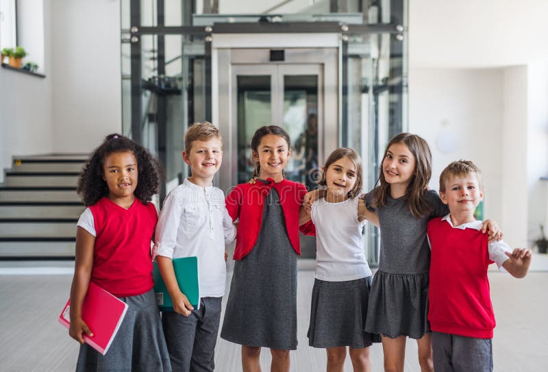 A Group of Cheerful Small School Kids in Corridor, Looking at Camera ...