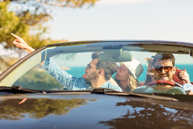 Group of Cheerful Young Friends Driving Car and Smiling in Summer Stock ...
