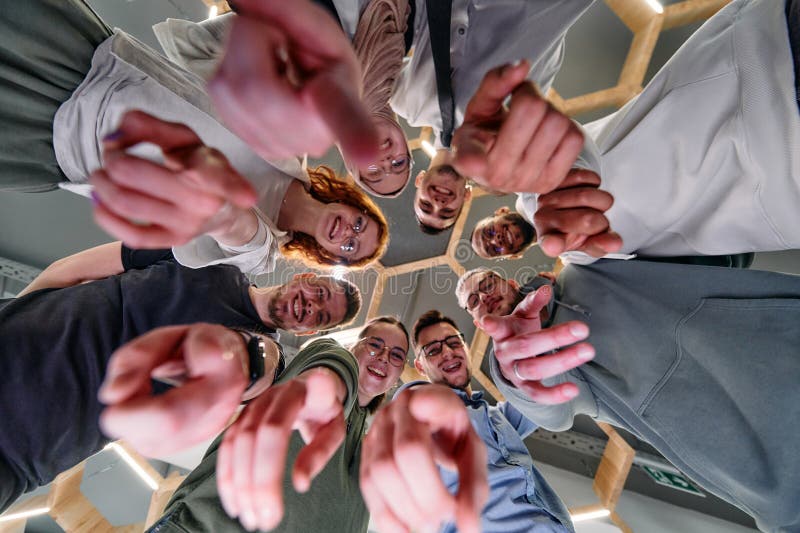 A Group of Cheerful Young People Gathered in a Circle, Pointing at the ...