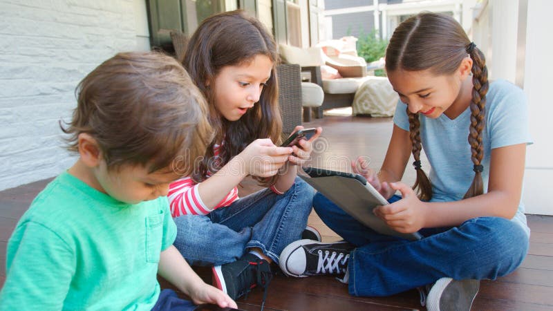 Group of Children Sit on Porch Playing with Digital Tablets and Mobile ...