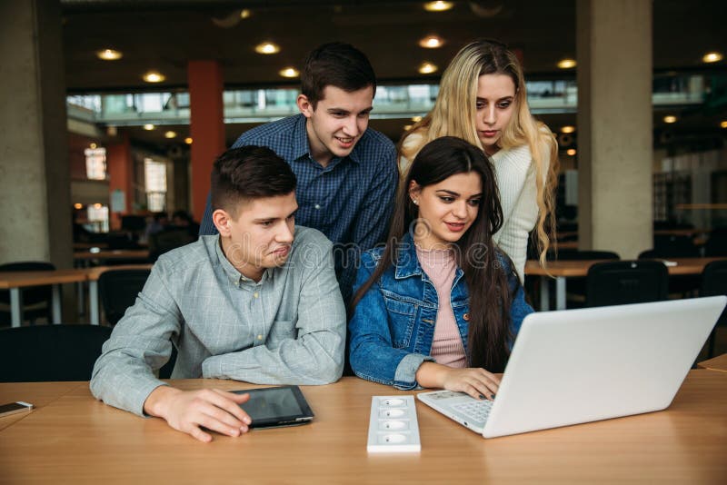 University Students Sitting Together At Table With Books And Laptop ...