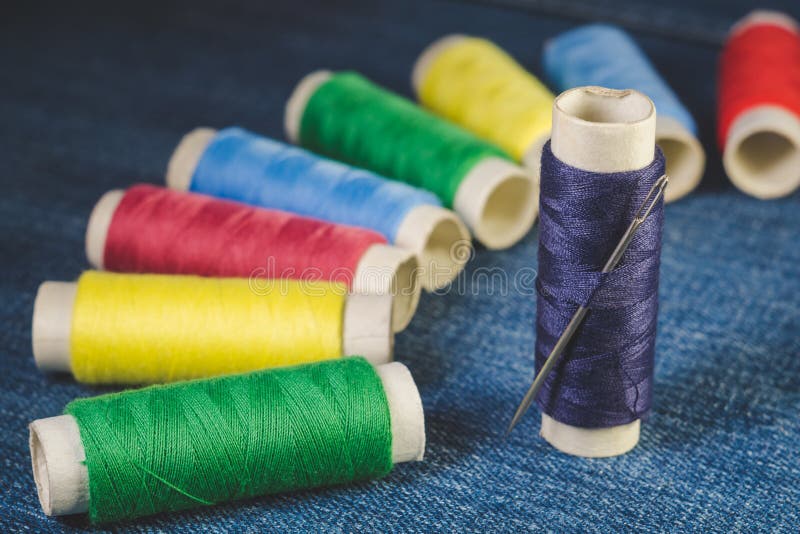 Group of Colored Thread Spools and Sewing Needle on Denim Stock Photo ...
