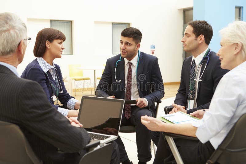 Group of Consultants Sitting at Table in Hospital Meeting Stock Photo ...