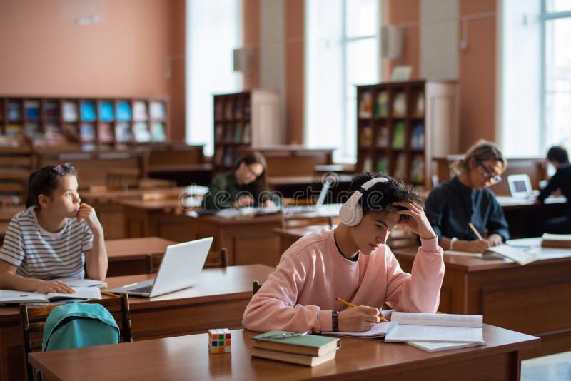 Group of Contemporary College Learners Sitting by Desks in Library ...