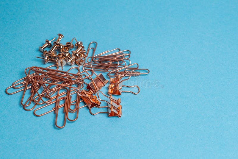 A Group of Copper Metal Staples, Clips, and Office Studs on a Blue ...