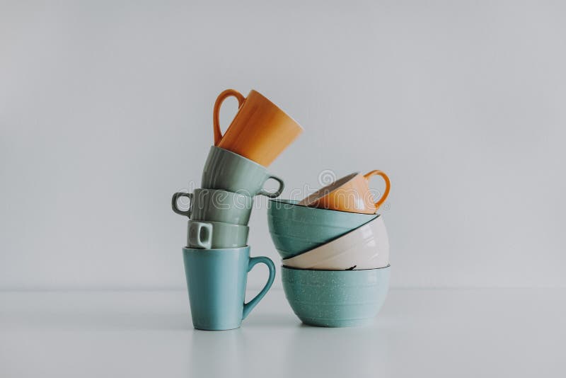 Group of Cups, Mugs, and Bowls Stacked on Top of Each Other on a Solid ...
