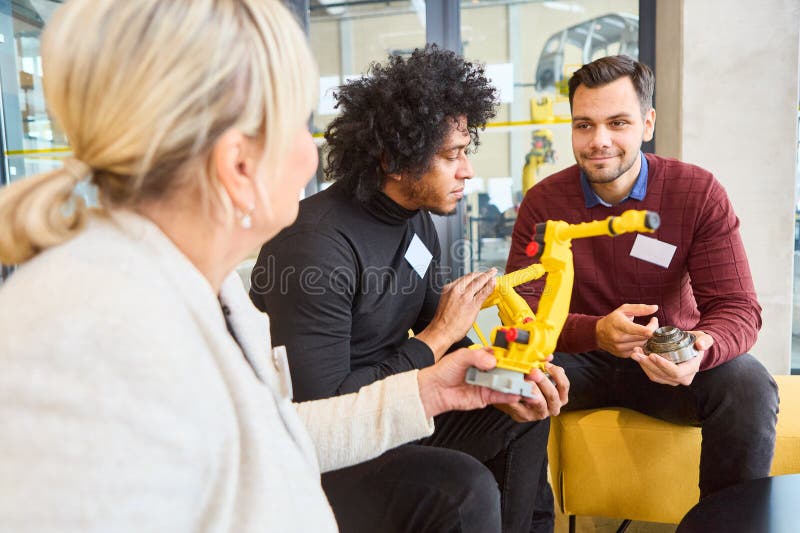 Group Discussing Robotics and Automation with a Model Robotic Arm Stock ...
