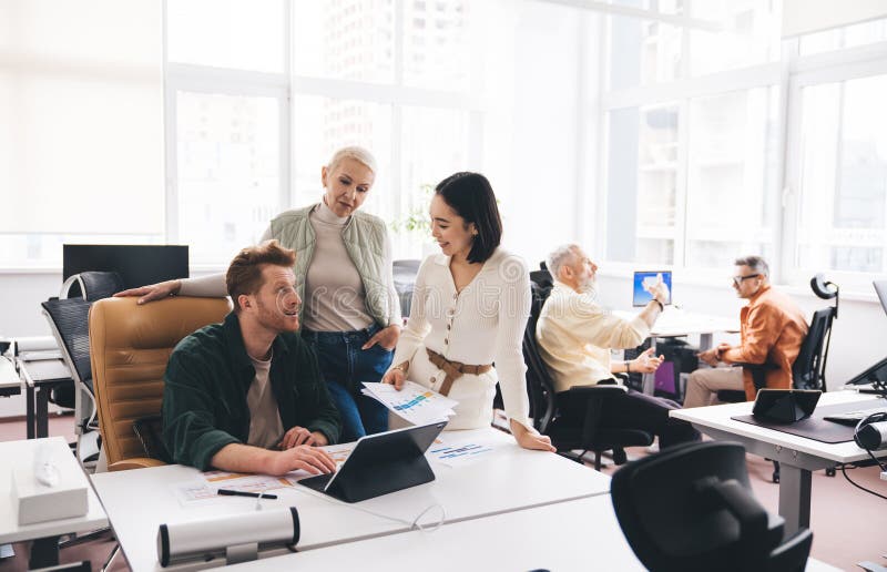 Group of Diverse Colleagues Discussing Work at Table with Laptop and ...