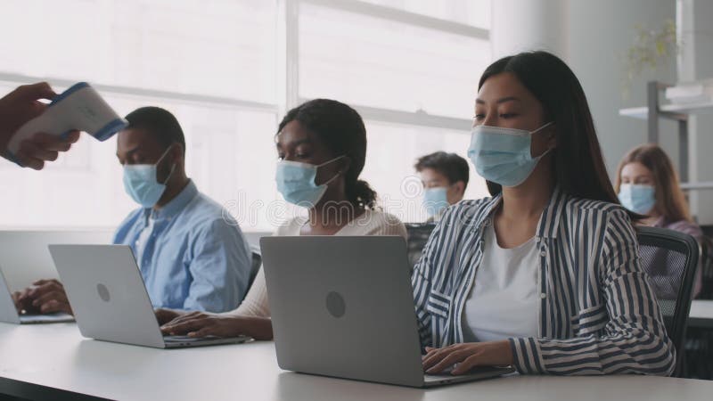 Group of Diverse Students in Protective Face Masks Typing on Laptops ...