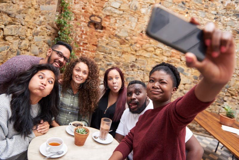 Friends Making Faces And Taking Selfies In A Cafe Courtyard Stock Image
