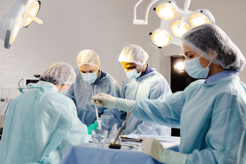 A Group of Doctors Wearing Masks are Standing Together Around a Table ...