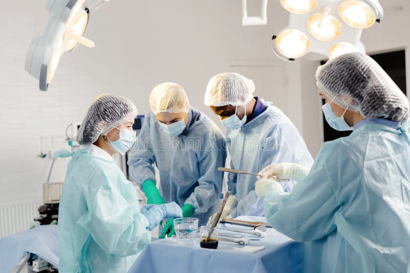 A Group of Doctors Wearing Masks are Standing Together Around a Table ...