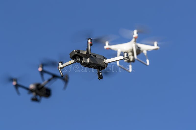A Group of Drones Fly Together through the Air Against a Blue Sky Stock ...