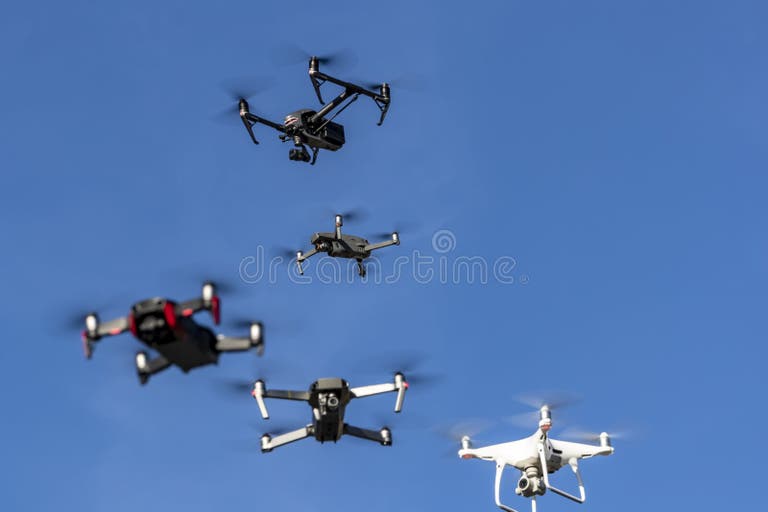 A Group of Drones Fly Together through the Air Against a Blue Sky Stock ...