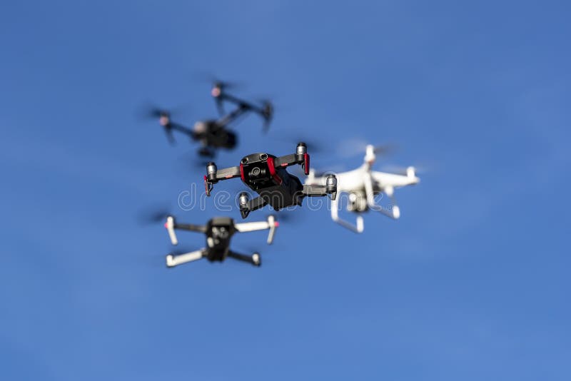 A Group of Drones Fly Together through the Air Against a Blue Sky Stock ...