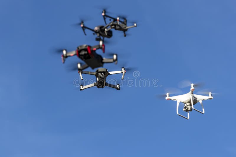 A Group of Drones Fly Together through the Air Against a Blue Sky Stock ...