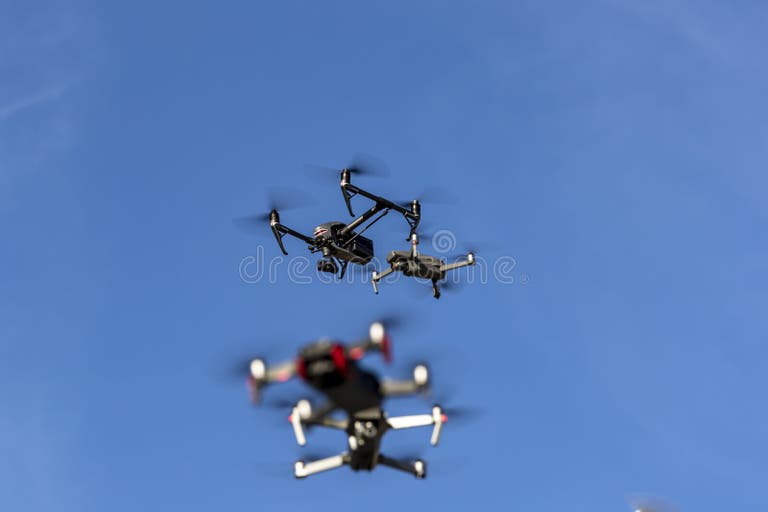 A Group of Drones Fly Together through the Air Against a Blue Sky Stock ...