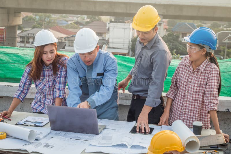 Group of Engineer Checking the Blueprint with Laptop and Talking about ...