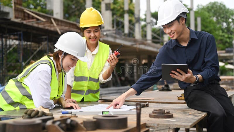 Group of Engineer in Safety Helmet Looking at Blueprints and Discussing ...