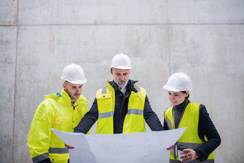 A Group of Engineers Standing Against Concrete Wall on Construction ...