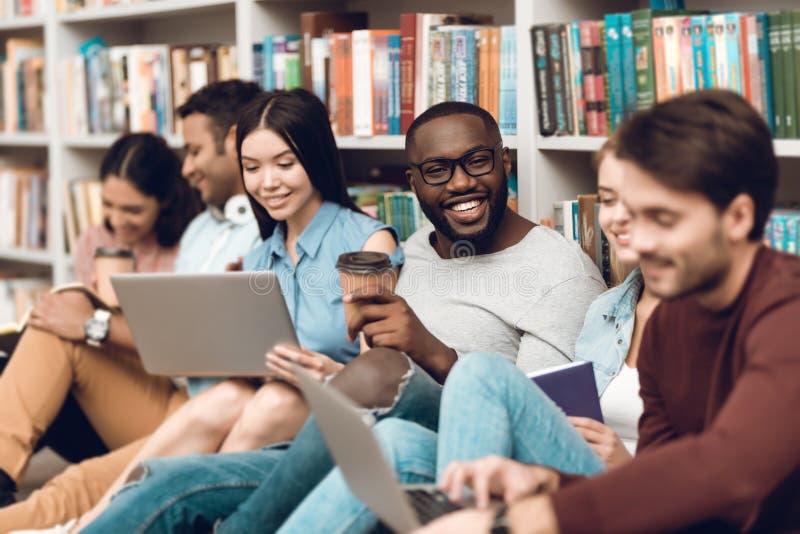 Group of Ethnic Multicultural Students Sitting Near Bookshelf in ...
