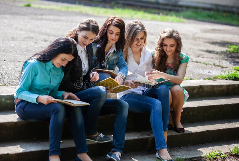 A Group of Female Students Sitting with Books in the Courtyard of the ...
