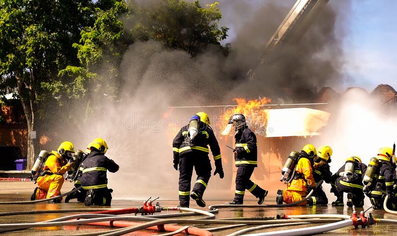 Group of Firefighters Fighting a Fire and Spraying High Pressure Water ...
