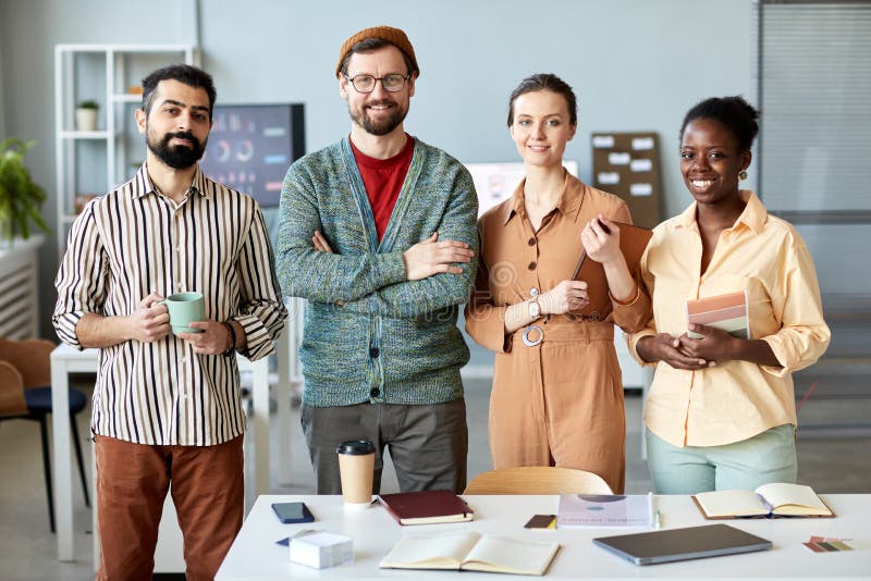 Group of Four Young Intercultural Designers Standing by Workplace in ... Group of Four Young Intercultural Designers Standing by Workplace in ...
