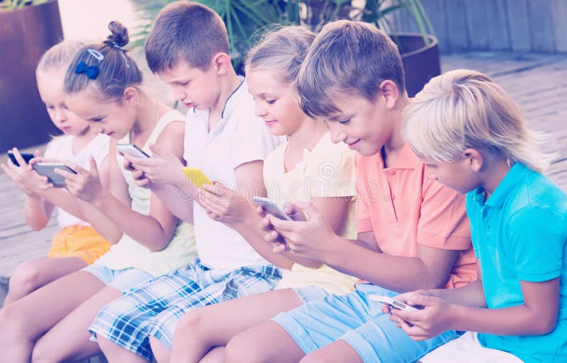 Group of Friendly Kids Playing with Mobile Phones Outdoors Stock Photo ...