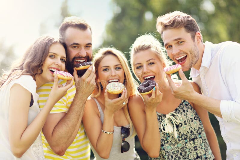 Group of Friends Eating Donuts Outdoors Stock Photo - Image of group ...