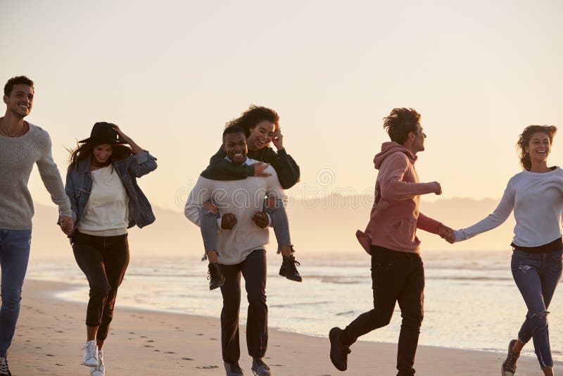 Group of Friends Having Fun Running Along Winter Beach Together Stock ...