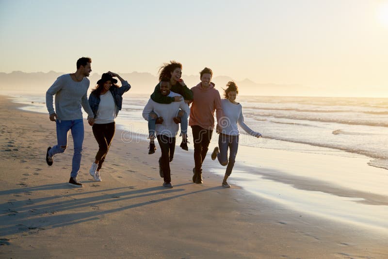 Group of Friends Having Fun Running Along Winter Beach Together Stock ...