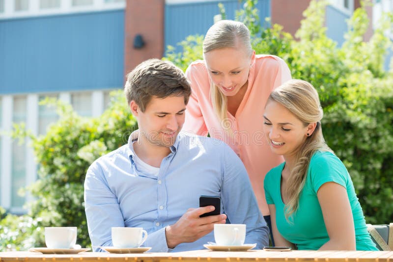 Group of Friends Looking at Mobile Phone Stock Photo - Image of smiling ...