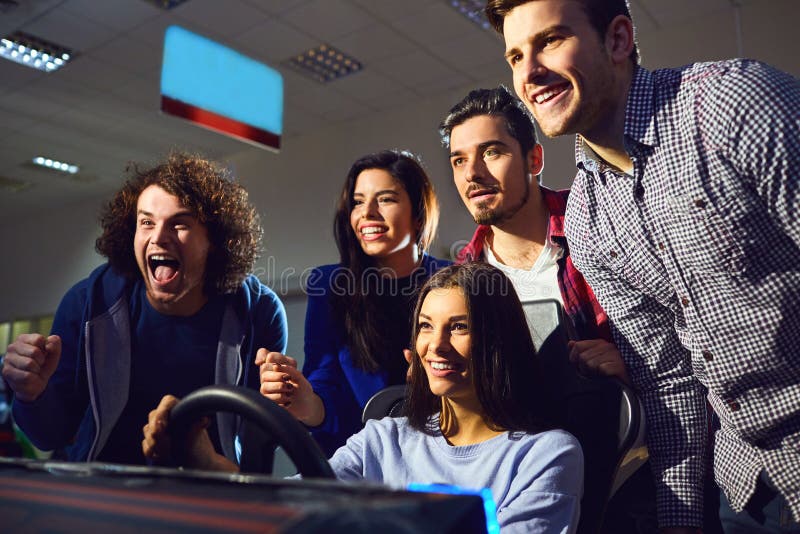 A Group of Friends Playing Arcade Machine. Stock Photo - Image of group ...