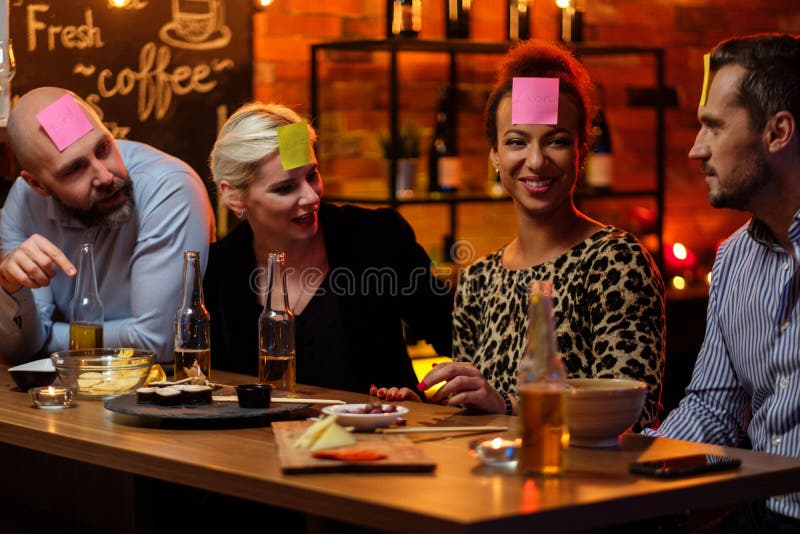 Group of Friends Playing Sticky Head Game Behind Bar Counter in a Cafe ...