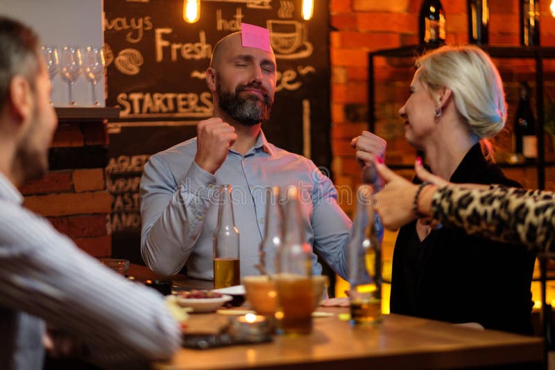 Group Of Friends Playing Sticky Head Game Behind Bar Counter In A Cafe ...