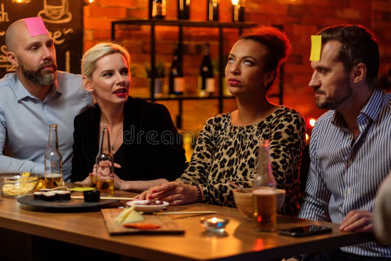 Group Of Friends Playing Sticky Head Game Behind Bar Counter In A Cafe ...