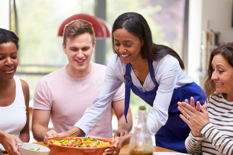 Group of Friends Sitting Around Table Eating Meal at Home Together ...