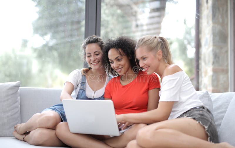 Group of Friends Smiling while Looking at the Computer and Sitting ...