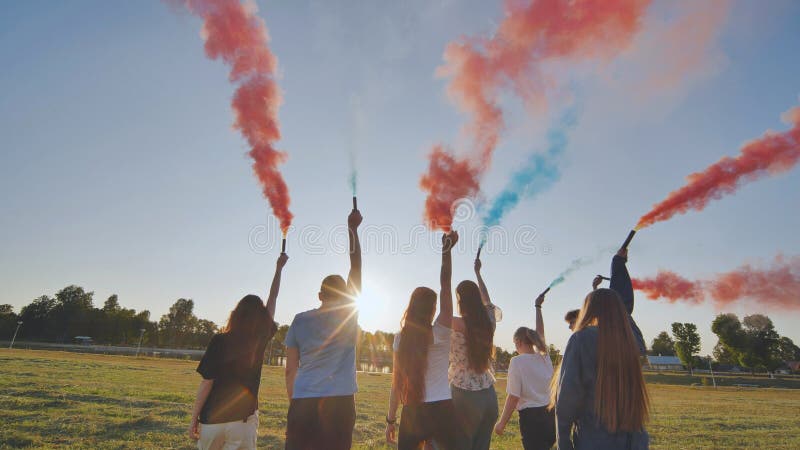 A Group of Friends Spraying Multi-colored Smoke at Sunset. Stock Image ...