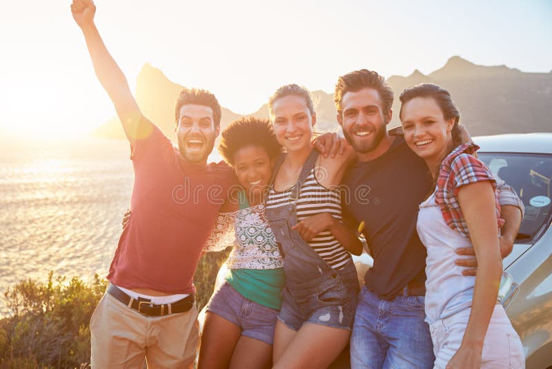 Group of Friends Standing by Car on Coastal Road at Sunset Stock Photo ...