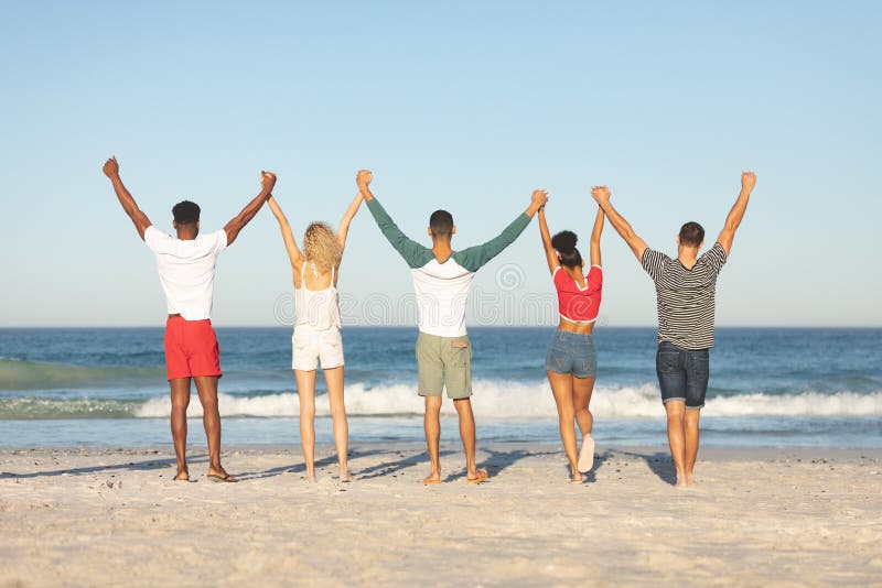 Group of Friends Standing Together with Hands Raised on the Beach Stock ...